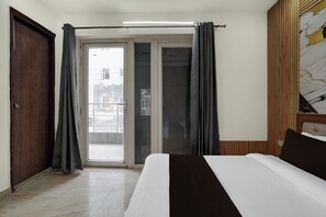 Quarto de hotel com cama, porta, porta de correr de vidro e vista para prédios.