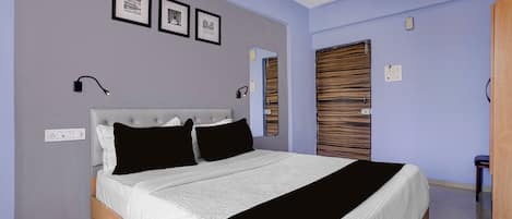 Quarto com cama, ventilador de teto, luminária na parede e quadros emoldurados.