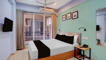 Quarto de hotel com cama, mesa de cabeceira com telefone, ventoinha no teto e janela com cortinas.