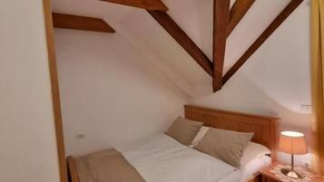 Quarto com cama de madeira, mesa de cabeceira com abajur e tapete macio no chão.