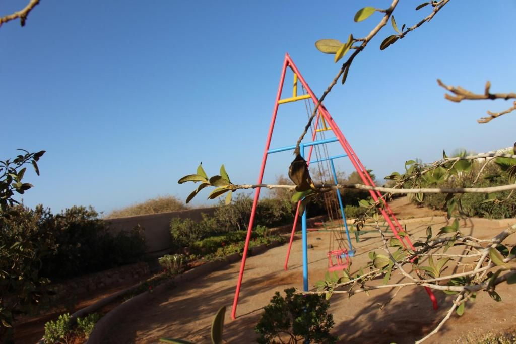 Um parquinho com estruturas de escalada e uma trilha de terra.