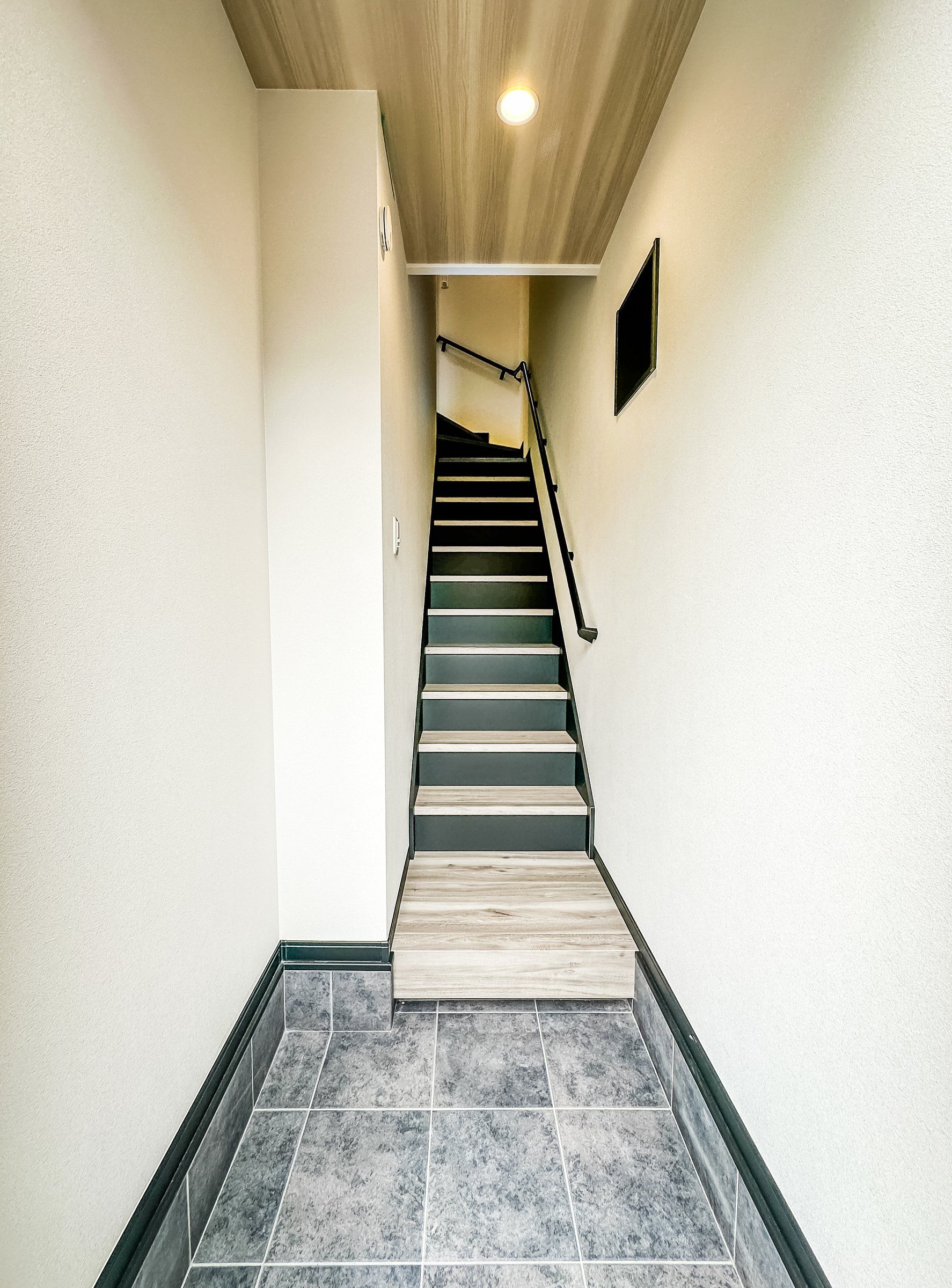 Uma escada com corrimão de madeira e piso de azulejos que leva a um patamar.
