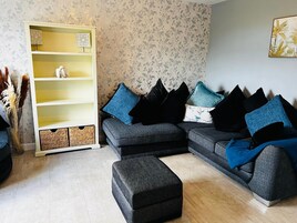 Sala de estar com sofá modular, estante branca e almofadas decorativas.