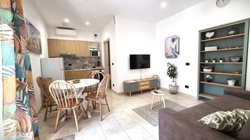 Um espaço de estar moderno com área de jantar, cozinha e espaço para sentar.
