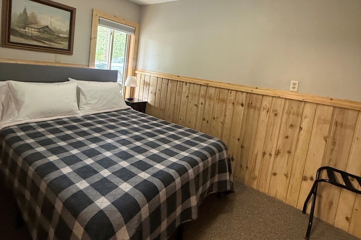 Quarto com cama, janela, quadro na parede e painel de parede de madeira.