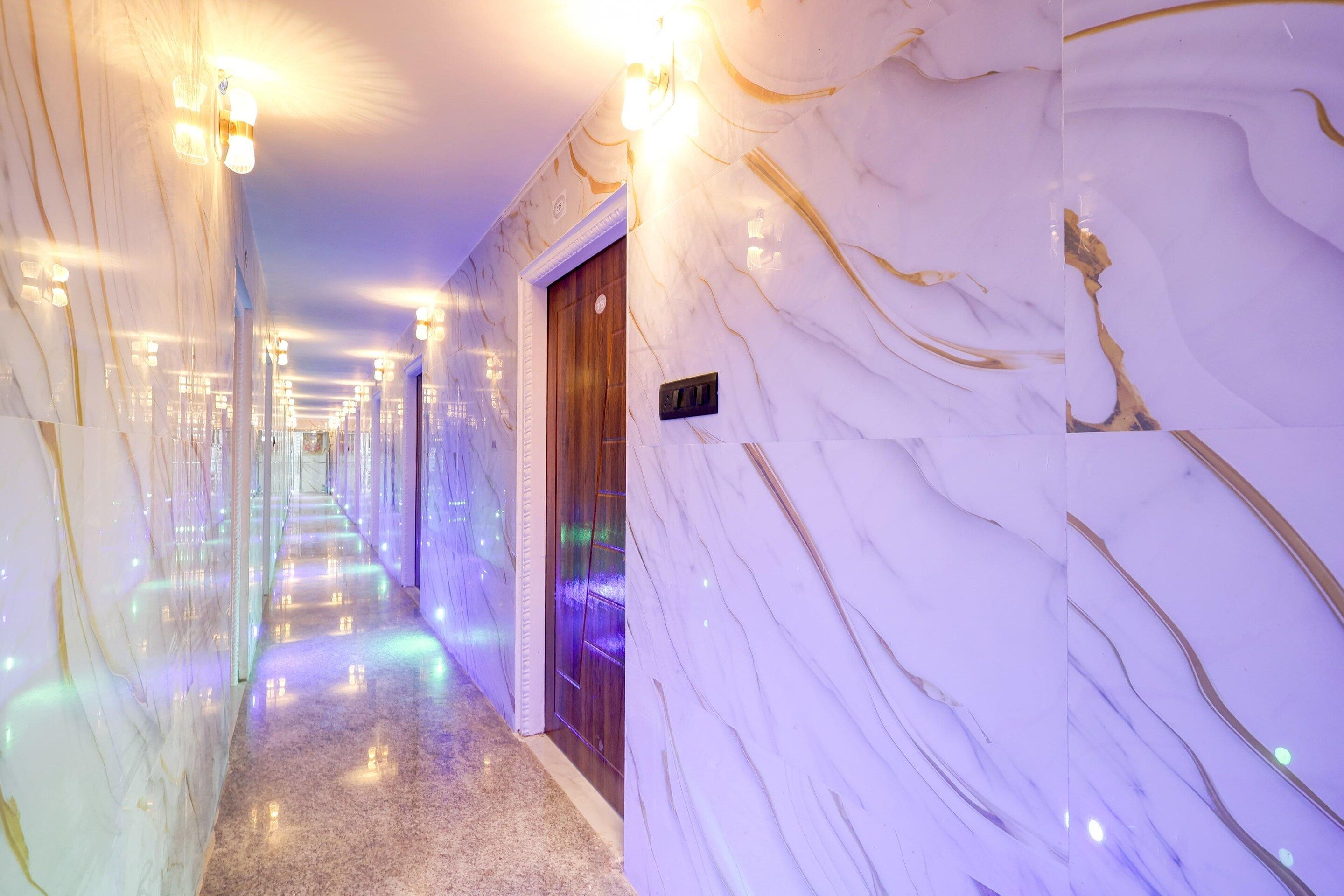 Um corredor de mármore com uma porta de madeira e um candeeiro.