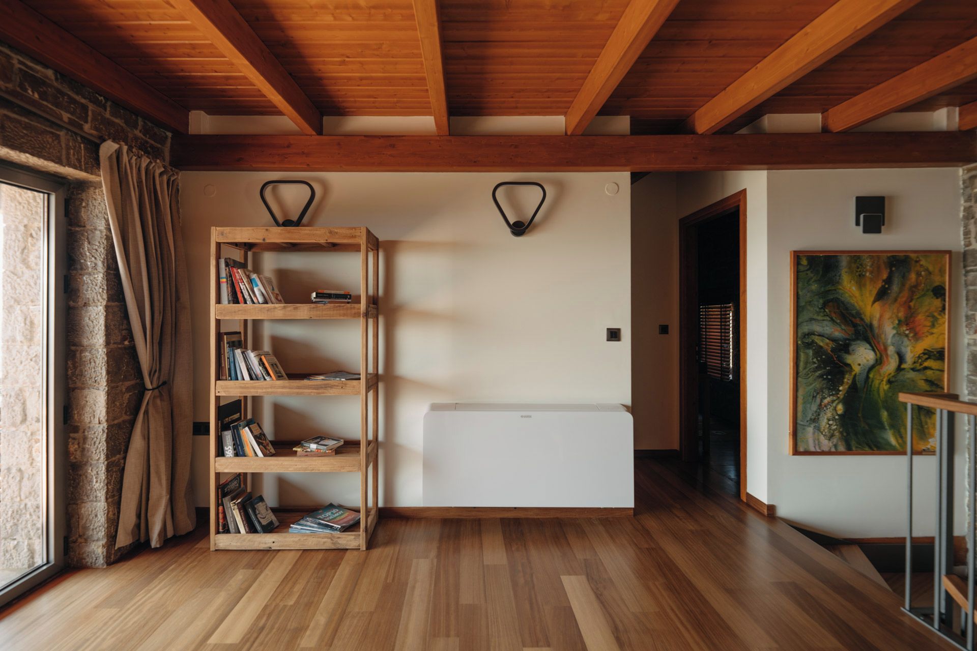 Quarto com estante de madeira, radiador branco e um quadro na parede.