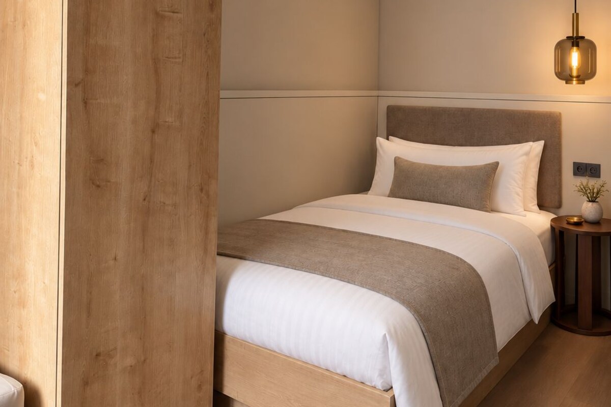 Quarto moderno com guarda-roupa de madeira, cama com cabeceira, mesa de cabeceira com abajur e uma pequena planta.