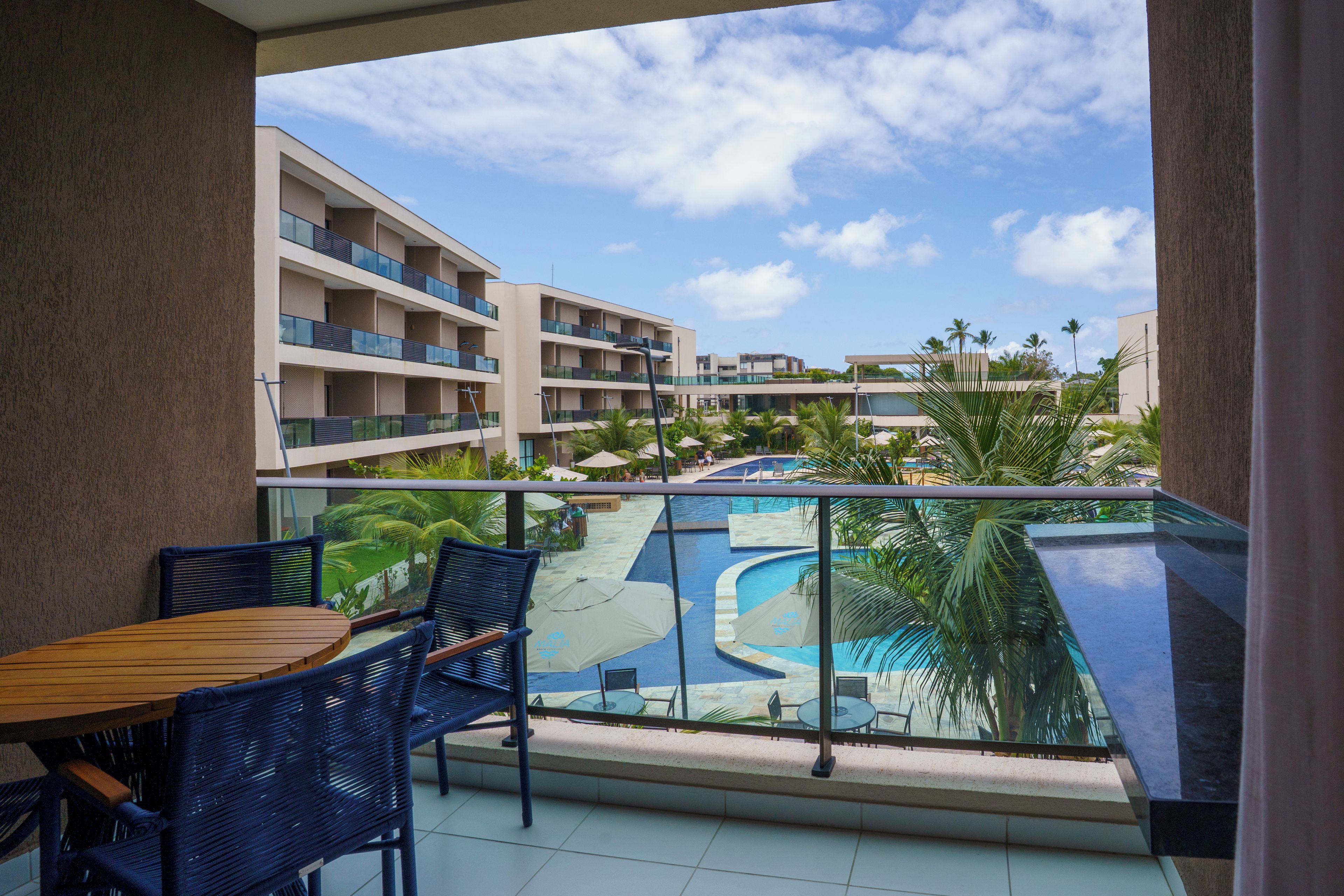 Varanda com piscina, cadeiras e vista para um edifício de hotel.