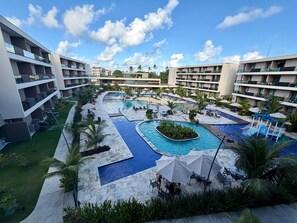Um hotel com várias piscinas, área de estar ao ar livre e palmeiras.