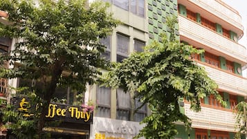 Vista da rua com uma cafeteria chamada 'Coffee Thuy' e vários scooters estacionados.