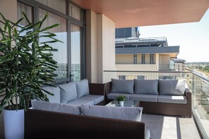 Varanda com sofá, planta em vaso e vista para a cidade.