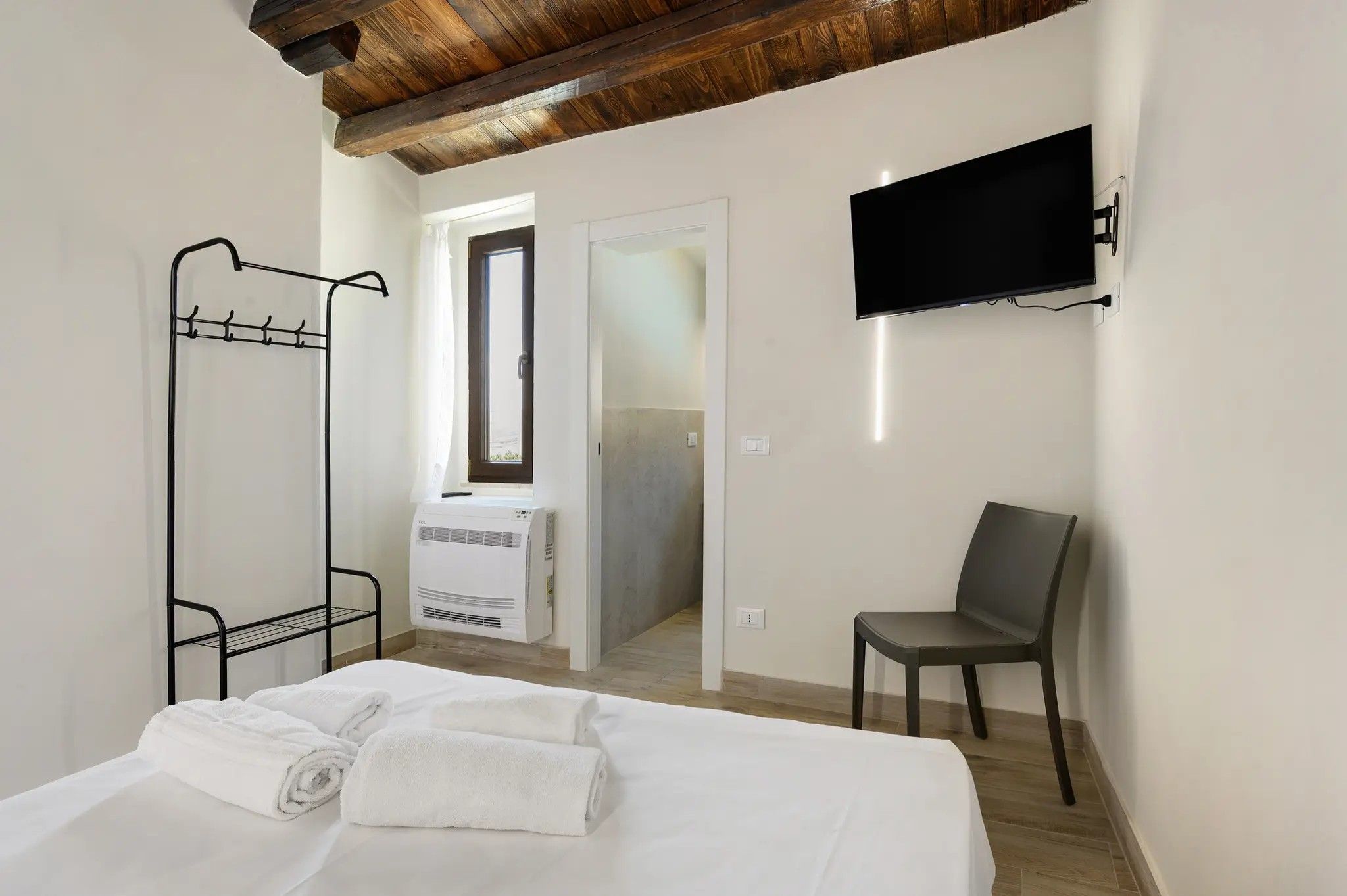 Quarto com cama, poltrona, televisão, guarda-roupa e ar condicionado.