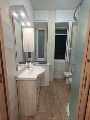 Uma casa de banho moderna com lavatório embutido, espelho, sanita e zona de duche.