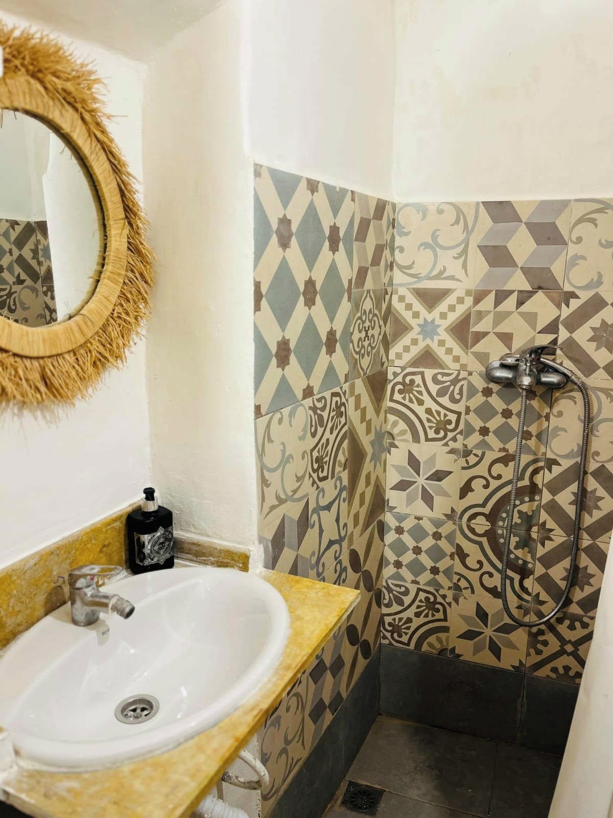 Casa de banho com lavatório, espelho e chuveiro.