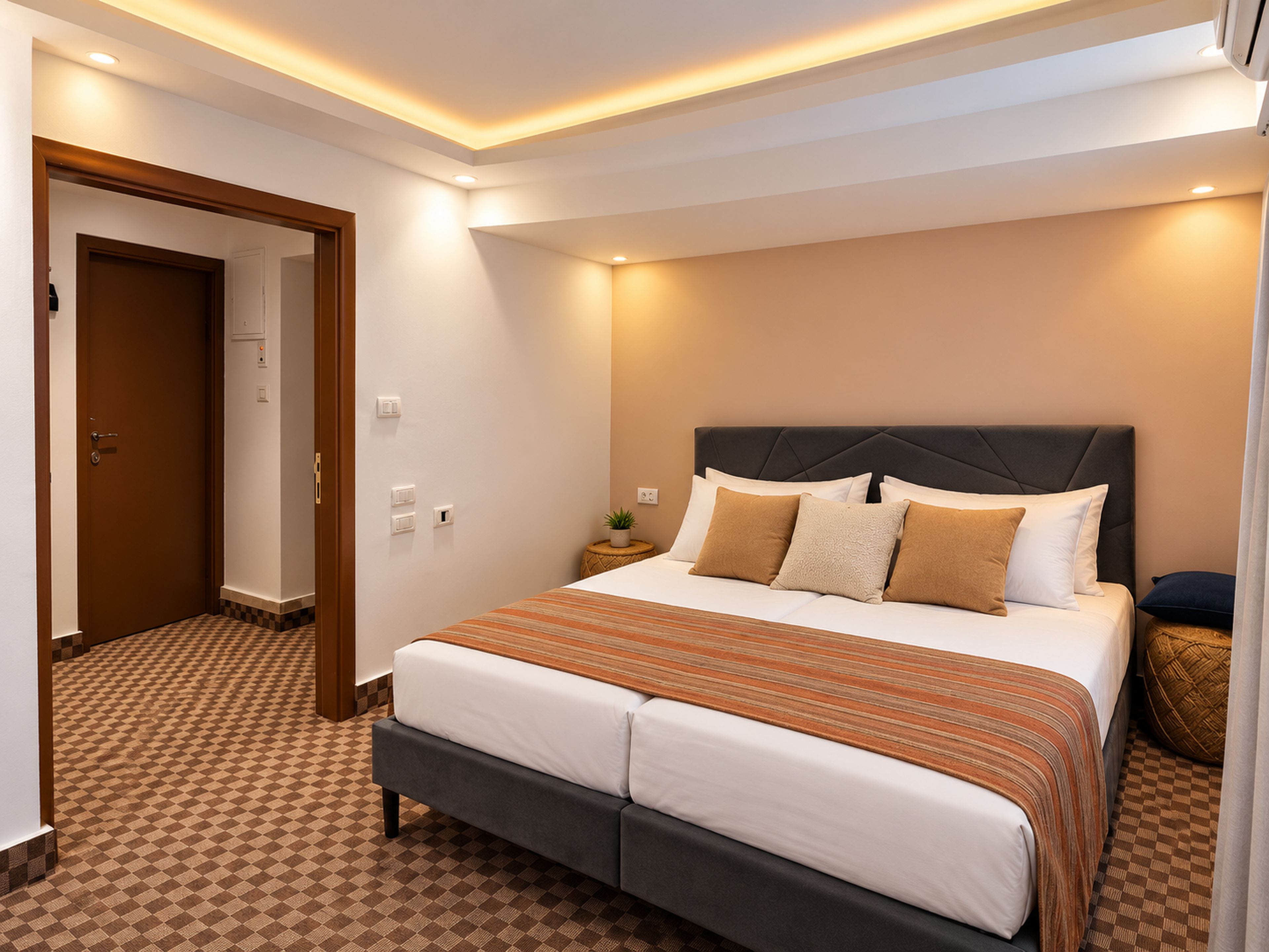 Quarto de hotel com uma cama grande, mesa de cabeceira e uma planta em vaso.