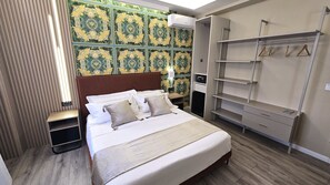 Quarto de hotel com uma cama grande, um guarda-roupa e um detalhe decorativo na parede.