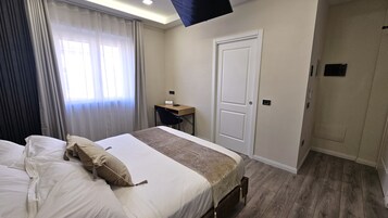 Quarto de hotel com cama, escrivaninha e porta.