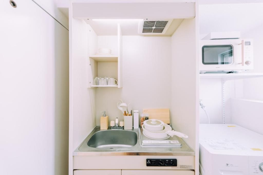 Uma cozinha compacta equipada com pia, micro-ondas e prateleiras de armazenamento.