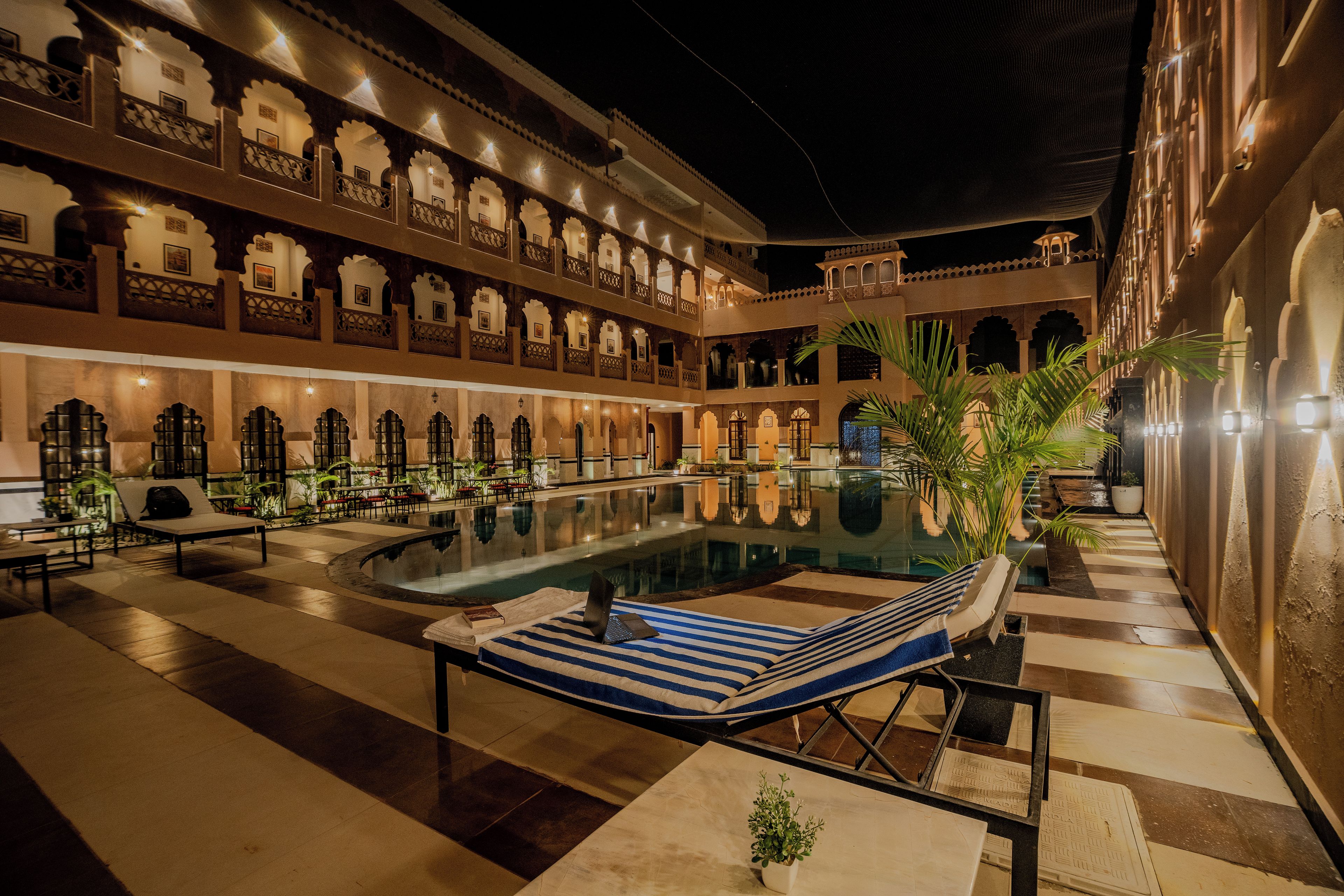 Um pátio com piscina, espreguiçadeiras e área de refeições.
