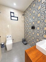 Casa de banho com sanita, bidé e lavatório com toucador de madeira.