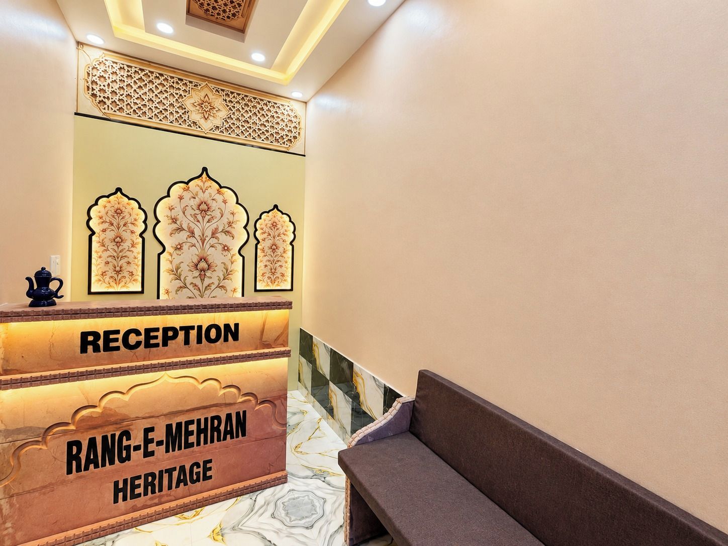 Uma área de recepção com um balcão identificado por 'RECEPTION' e 'RANG-E-MEHREN HERITAGE'.