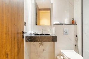 Casa de banho moderna com lavatório de mármore, sanita e zona de duche.