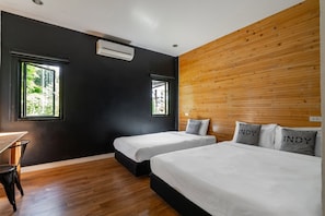 Quarto de hotel com duas camas, uma escrivaninha e uma janela.