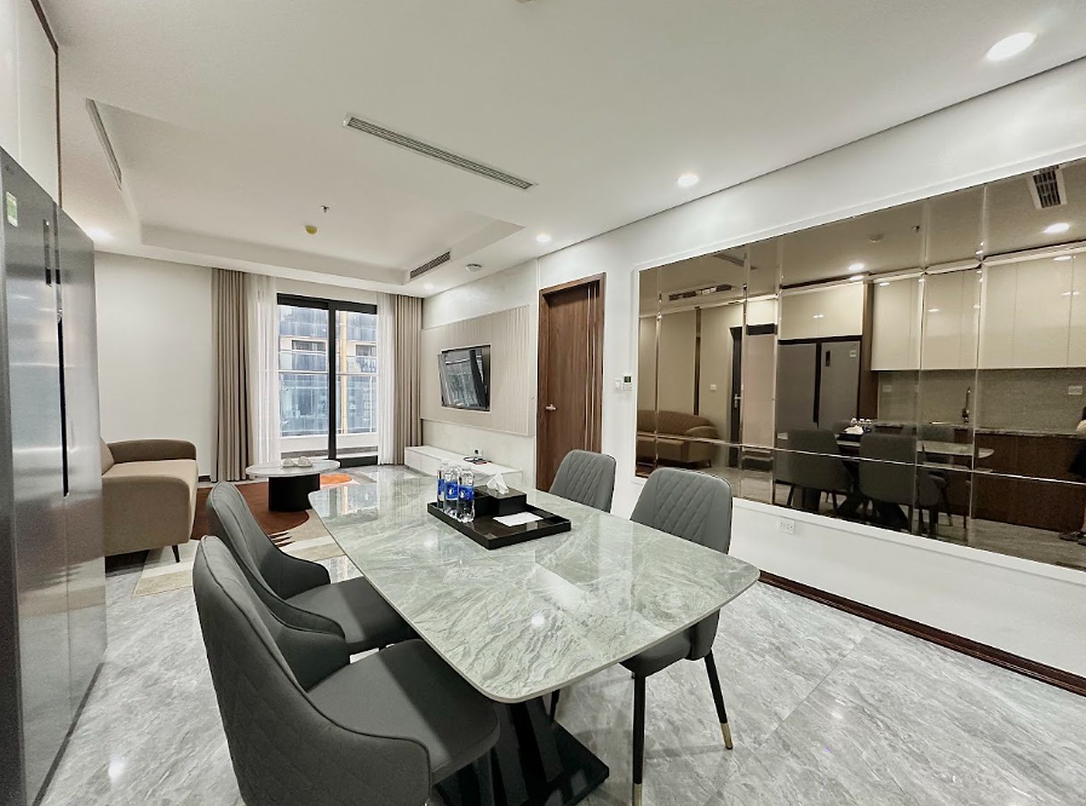 Uma sala de conferências moderna em hotel, com mesa de mármore, assentos confortáveis, televisão e vista para a paisagem urbana através de grandes janelas.