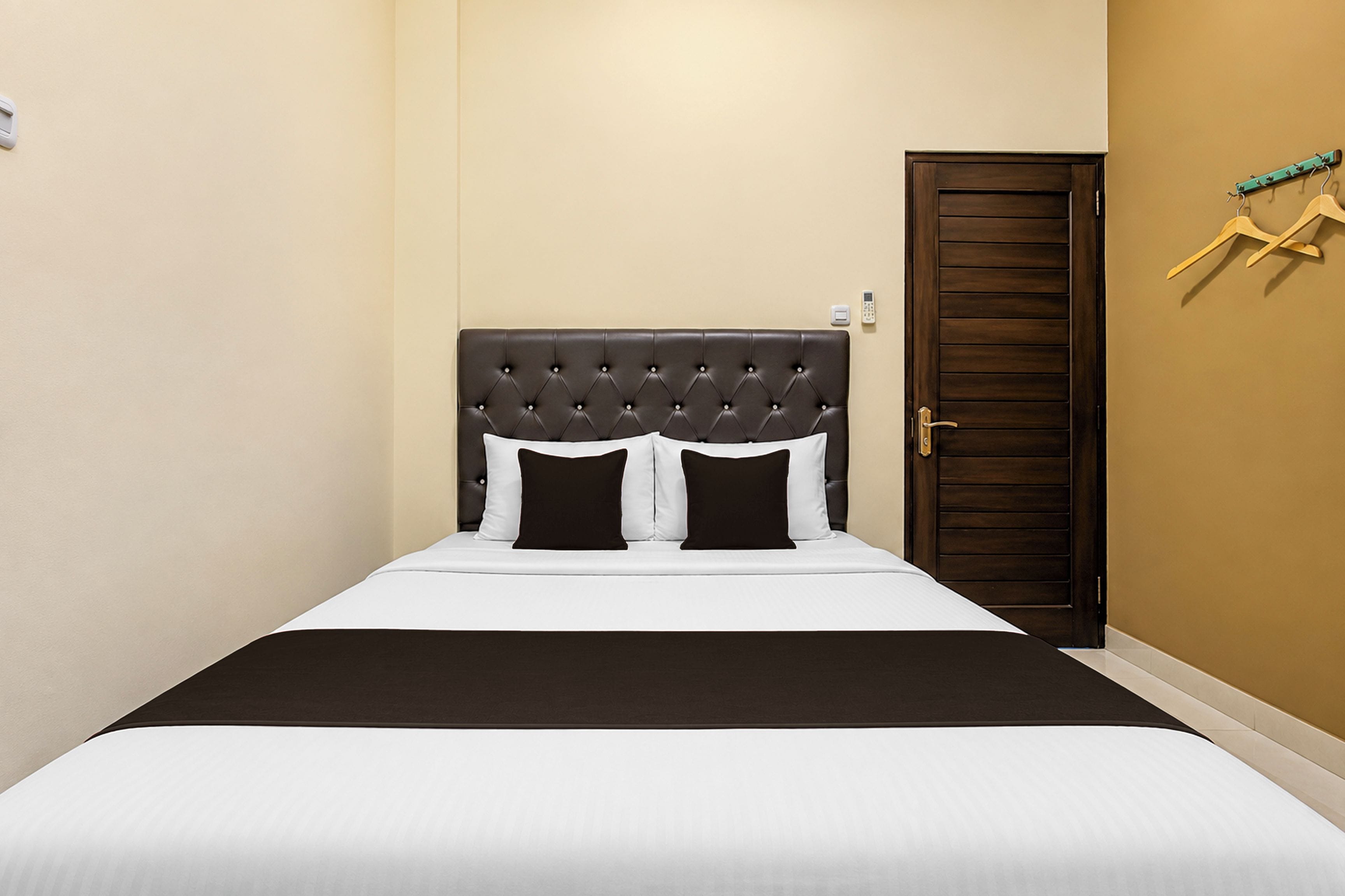 Quarto de hotel com cama, porta e cabideiro.