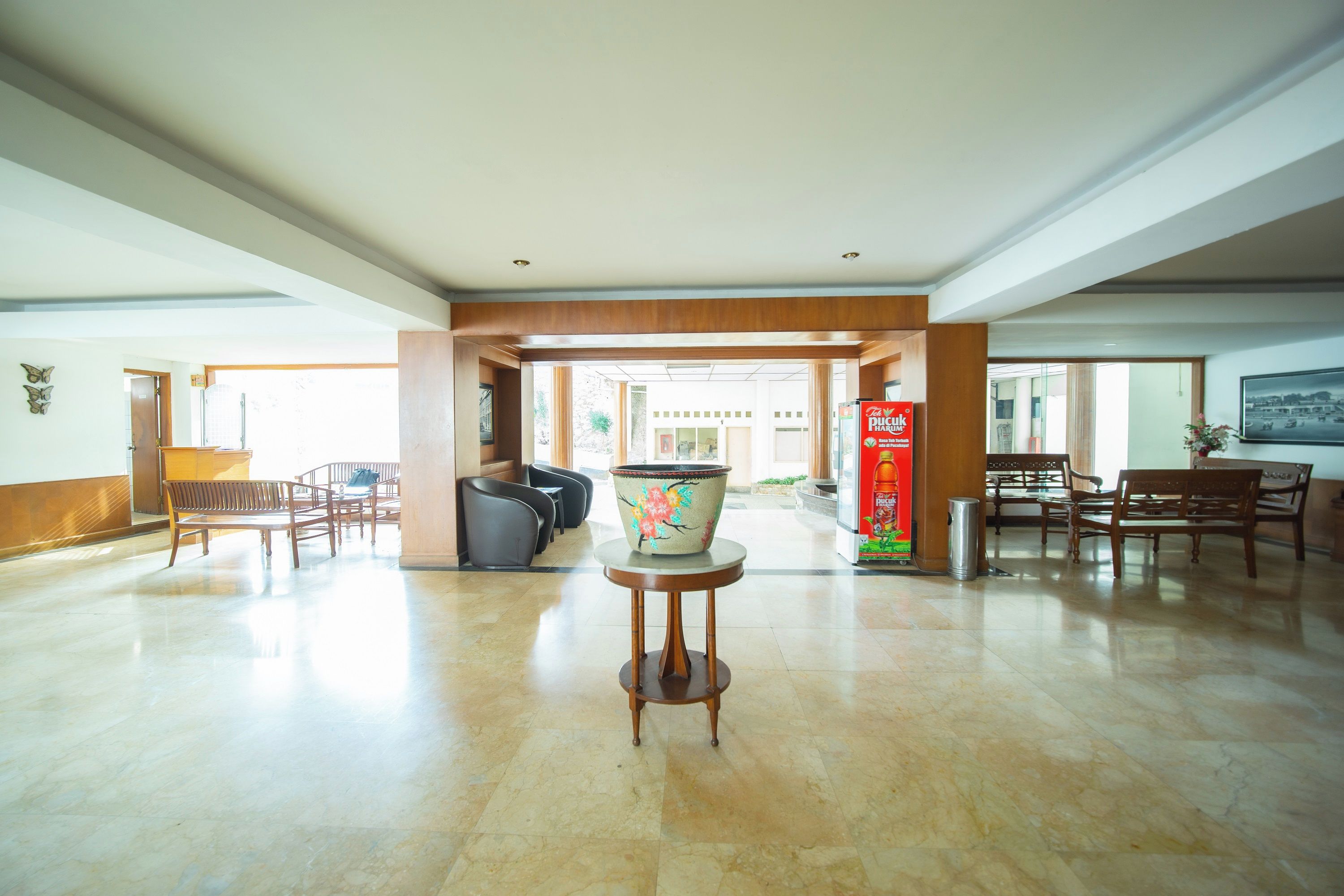 Um hall espaçoso com uma mesa central, área de estar e máquina de venda automática.