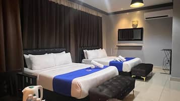Quarto de hotel com duas camas, uma mesa com apoio para garrafa de água e uma pequena área de estar.