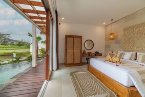Quarto com cama de madeira, vista para um corpo d'água e varanda.
