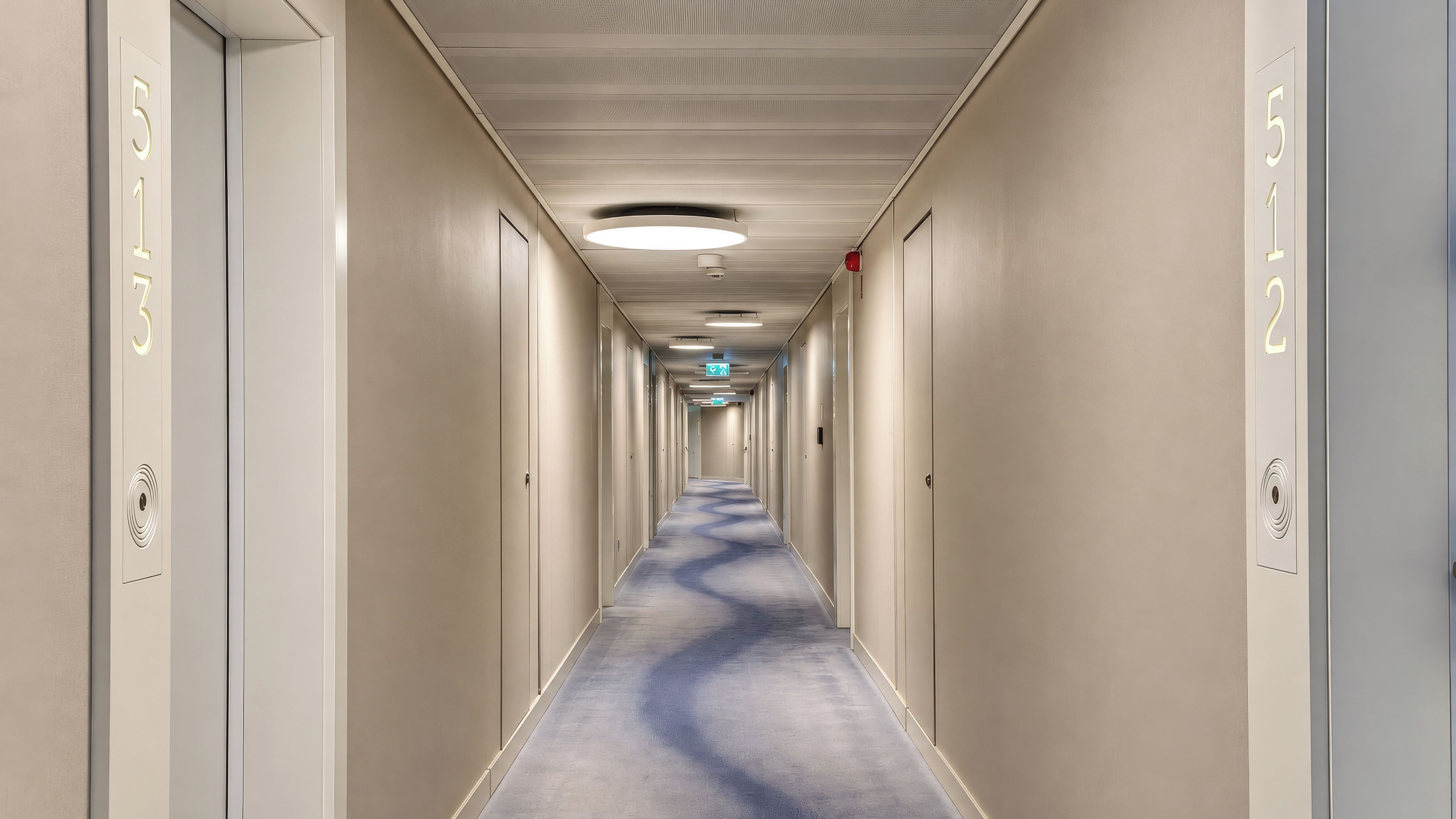 Corredor de hotel com portas numeradas 5, 17, 2 e 10, e um tapete azul.