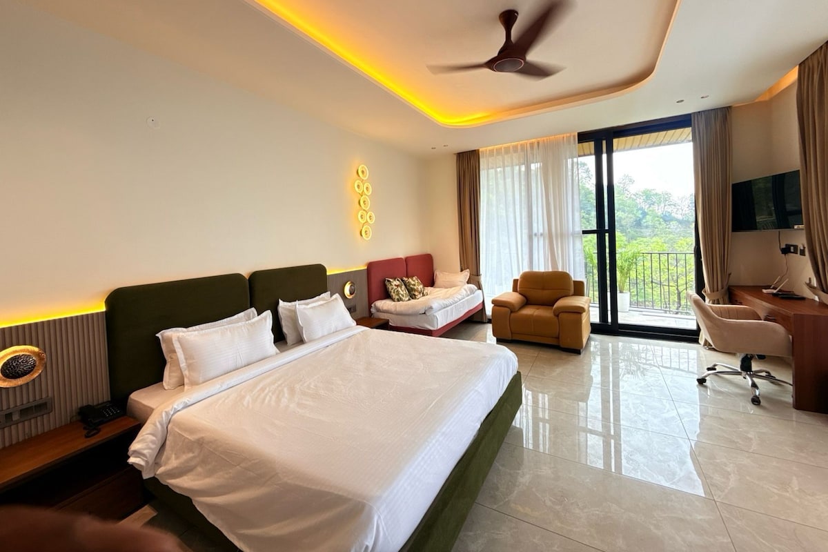 Quarto de hotel com uma cama grande, uma escrivaninha, uma cadeira e uma varanda com vista.