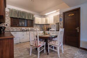 Uma cozinha com armários brancos, uma mesa de jantar com cadeiras floridas e uma porta com a inscrição 'OAK'.