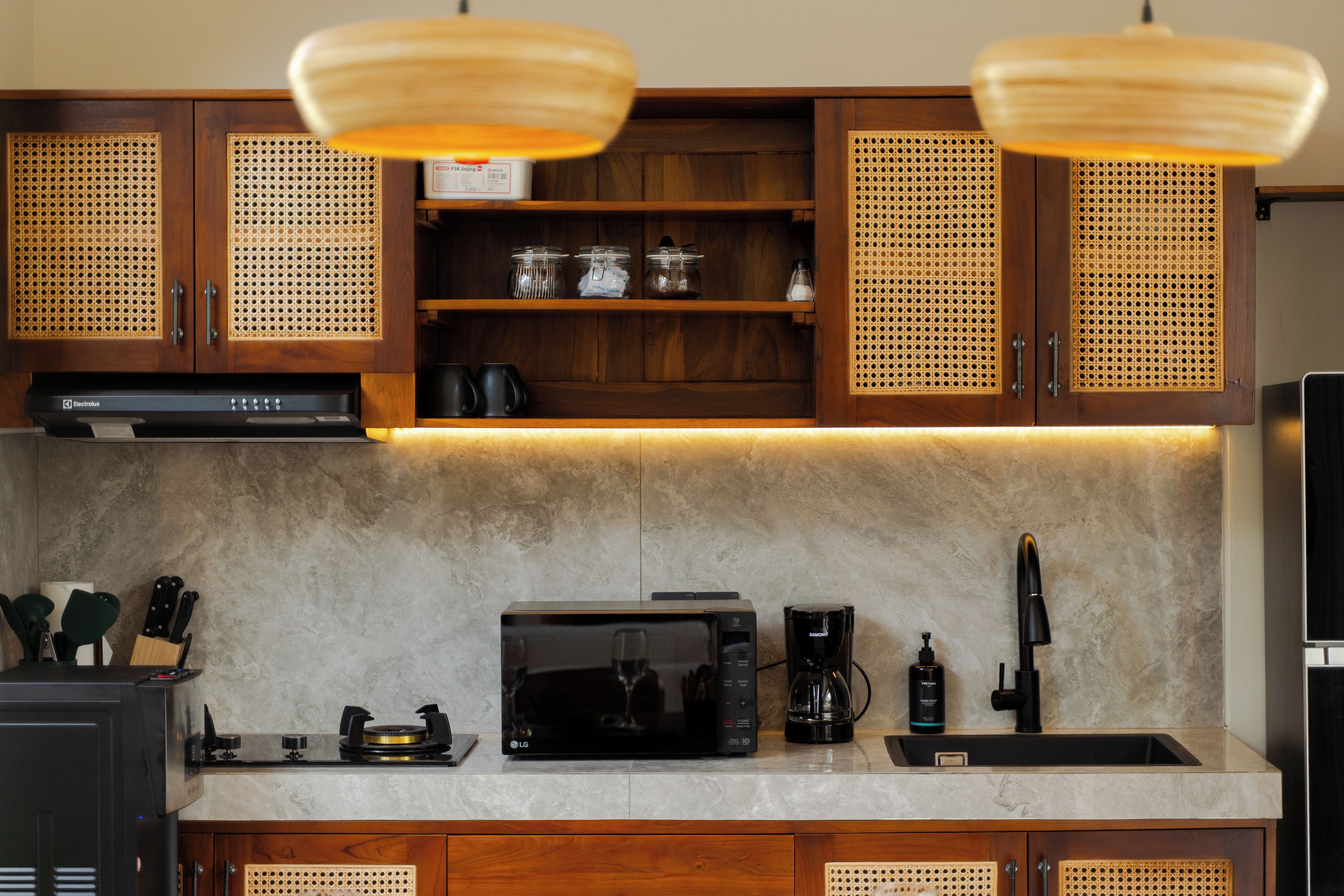 Cozinha com armários de madeira, micro-ondas, cafeteira e fogão a gás.