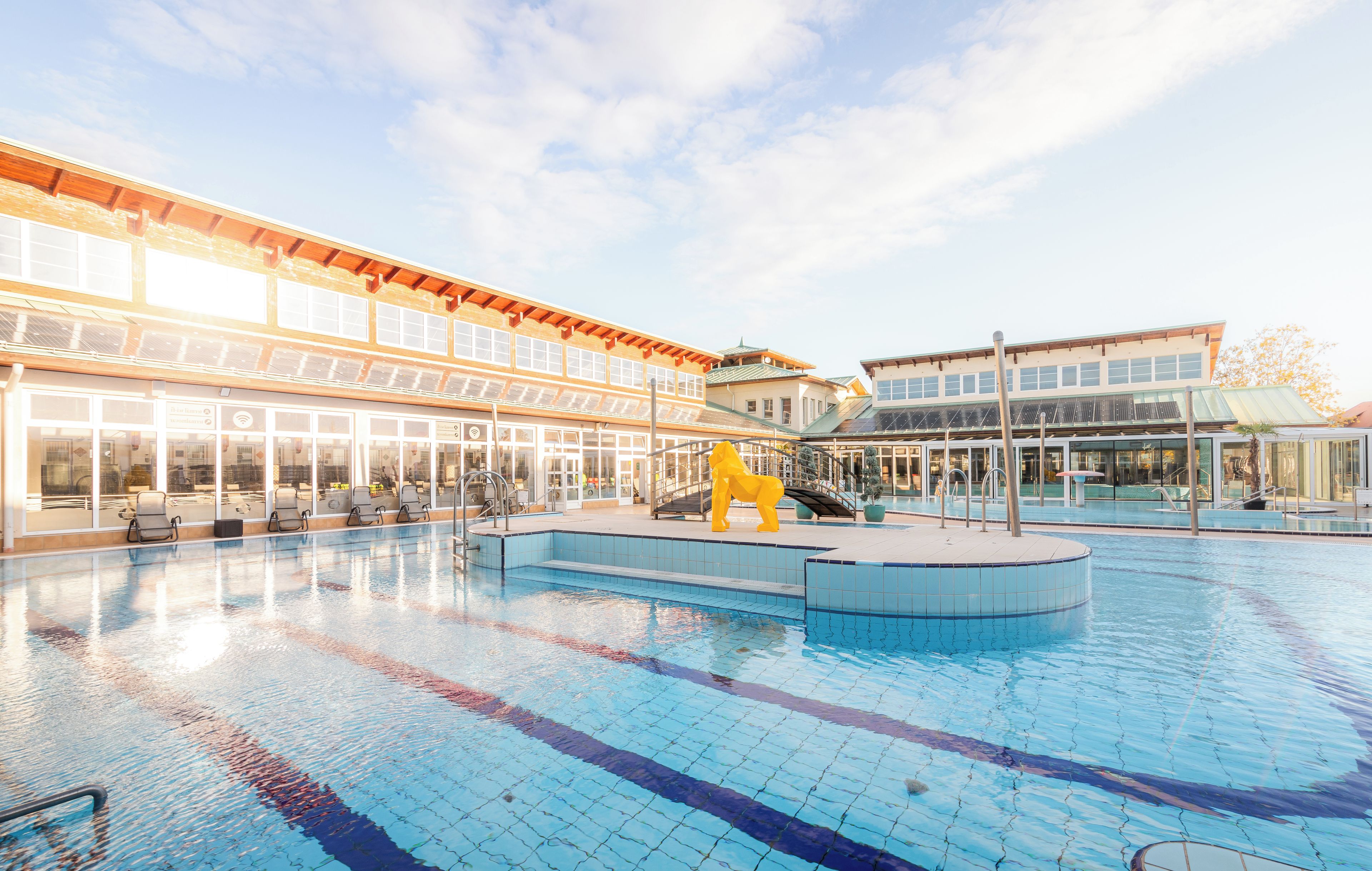 Uma piscina com uma cadeira de salva-vidas e uma estátua amarela.