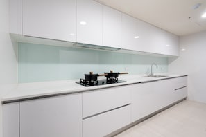 Cozinha moderna com armários brancos, uma pia de aço inoxidável e um fogão a gás.
