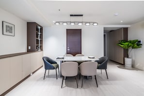 Uma sala de jantar moderna com uma mesa retangular, seis cadeiras e um lustre no teto.