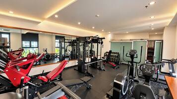 Uma academia com diversos equipamentos de exercício, um espelho e vista para o exterior.