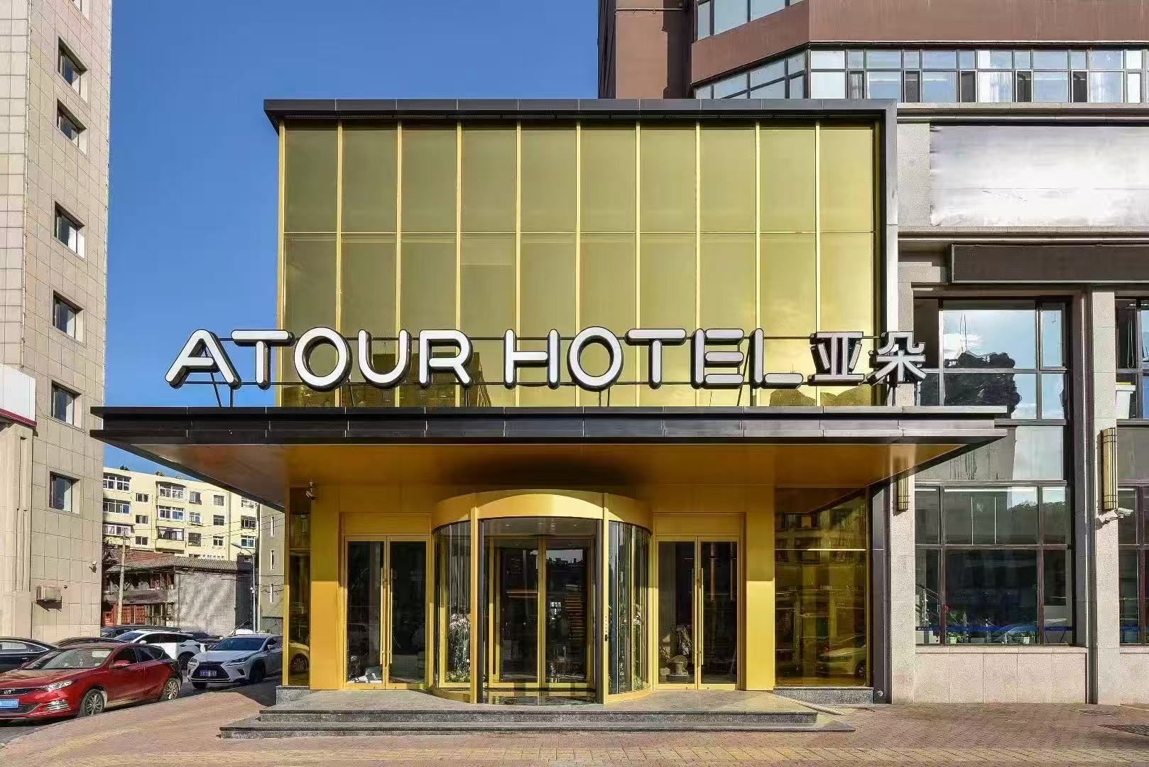 Entrada de hotel com design moderno, destacando uma placa e fachada de vidro.