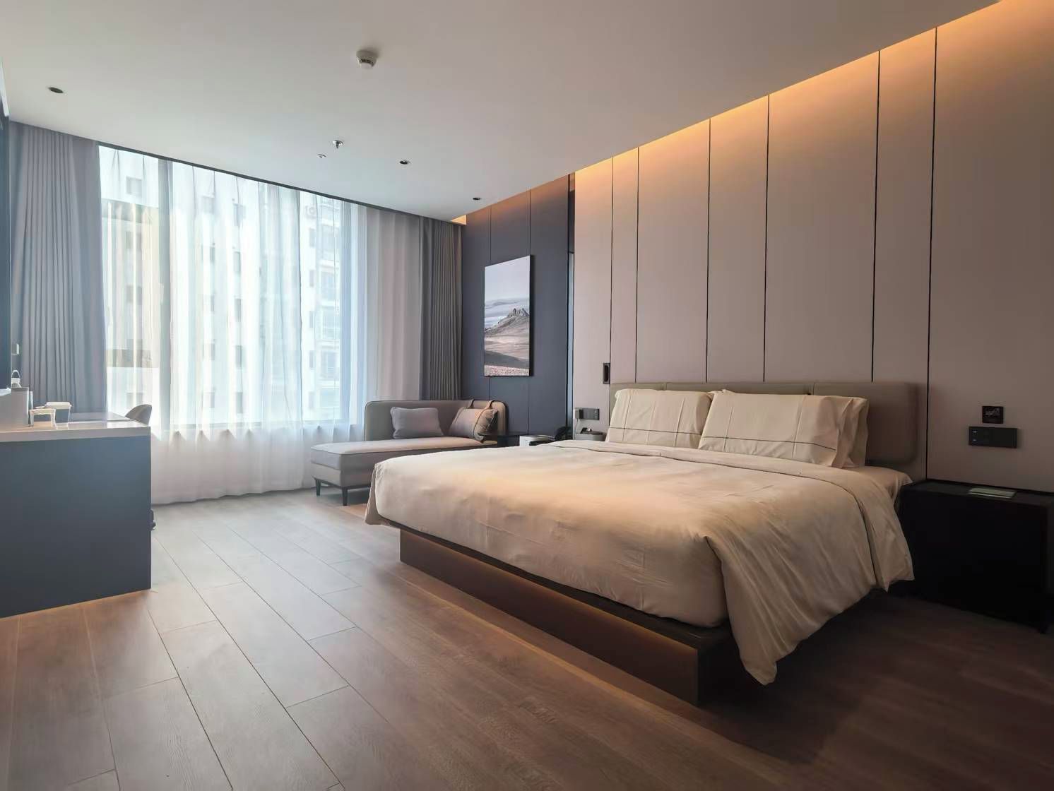 Quarto moderno com uma cama grande, área de estar e uma mesa de trabalho.