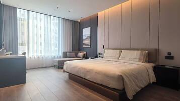 Quarto moderno com uma cama grande, área de estar e uma mesa de trabalho.