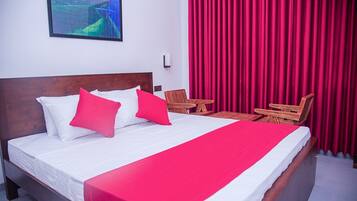Quarto de hotel com uma cama grande, cortinas vermelhas, cabeceira de madeira e um quadro na parede.
