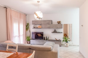 Uma sala de estar moderna com sofá, televisão e objetos decorativos.