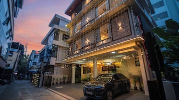 Um edifício moderno com um carro estacionado em frente, uma placa visível e fachada de tijolos.