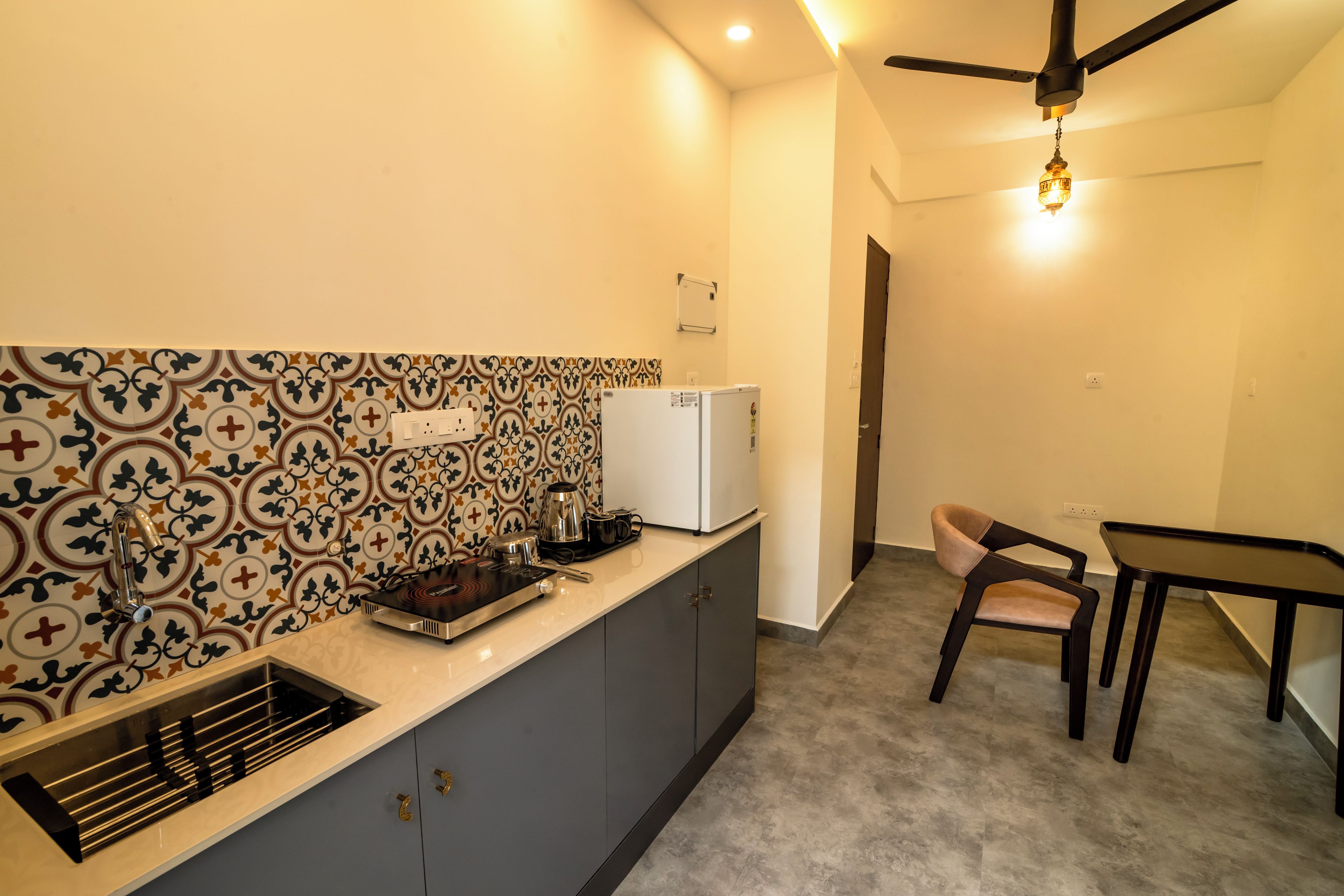 Cozinha compacta com painel decorativo, forno embutido e área de refeições com mesa e cadeiras.