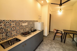 Cozinha compacta com painel decorativo, forno embutido e área de refeições com mesa e cadeiras.