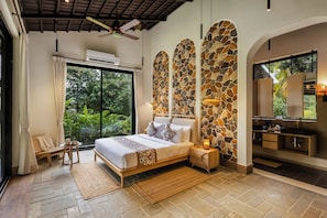 Quarto com cama, mesa de cabeceira e vista para o exterior.